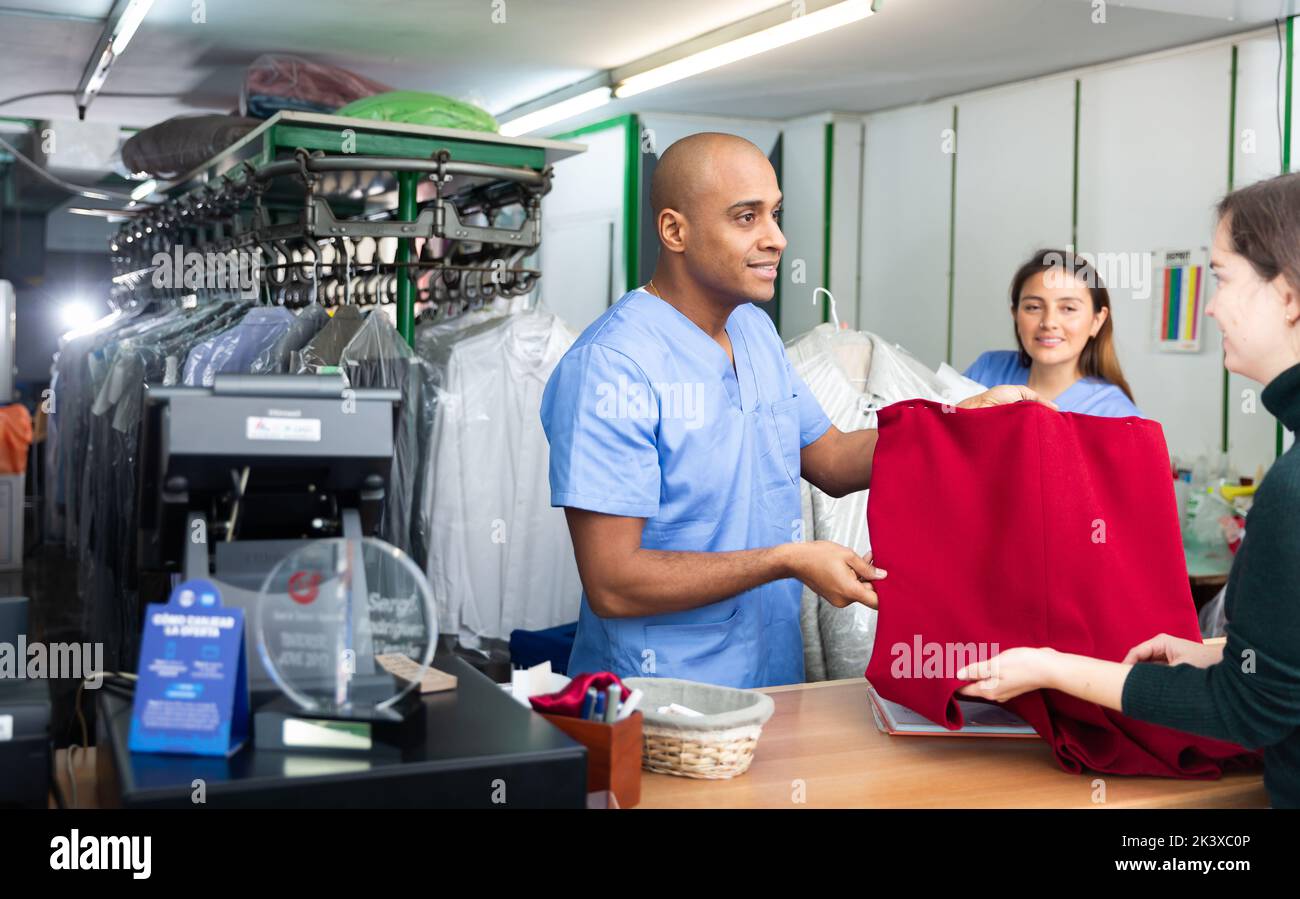 Ordinary woman and man working with client in modern laundry Stock ...