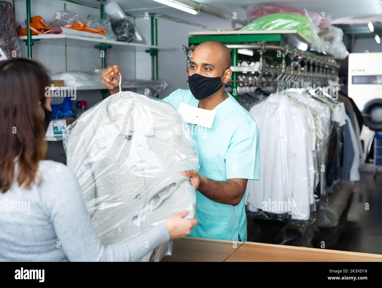 Man dry-cleaning worker giving clothes to customer Stock Photo - Alamy