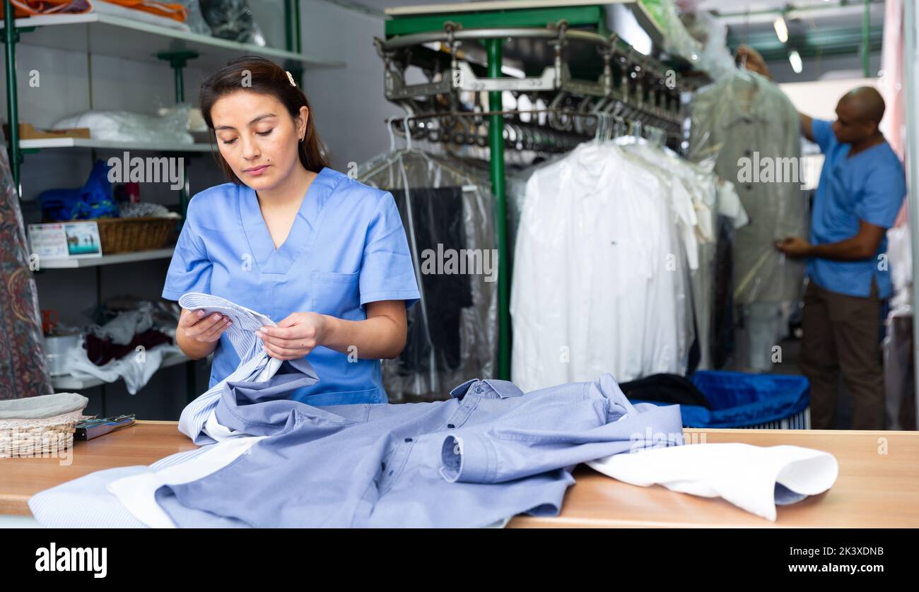 Portrait of female laundry worker examining clean garments Stock Photo ...