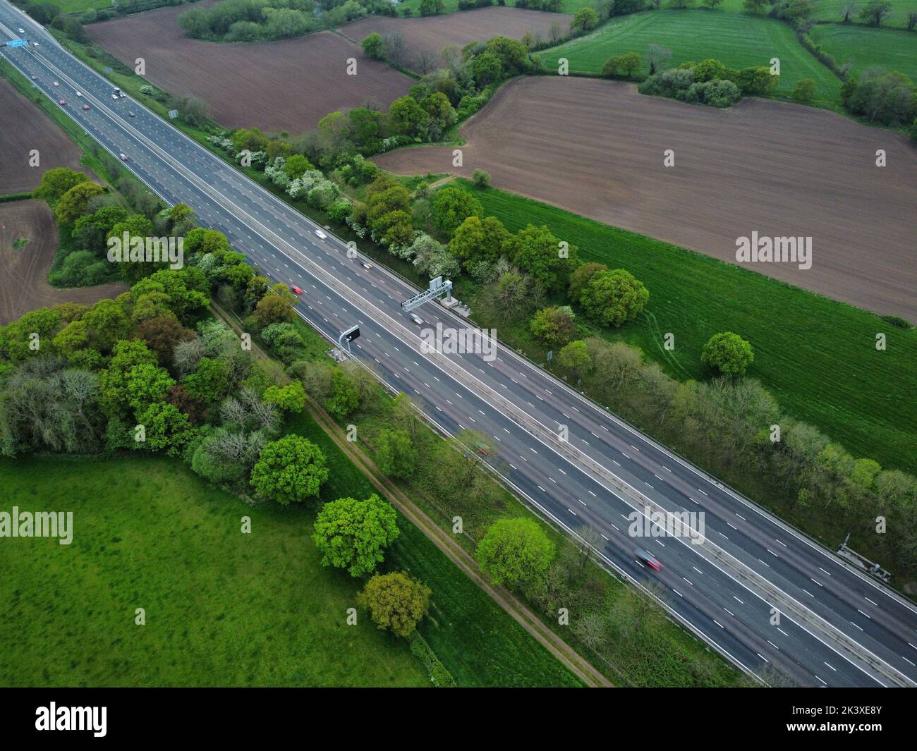An aerial shot of a highway surrounded by green trees and a dry sandy ...