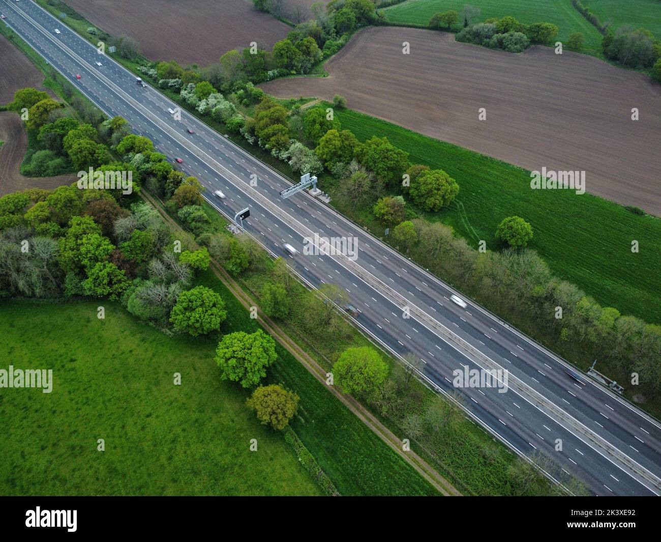 An aerial shot of a highway surrounded by green trees and a dry sandy ...
