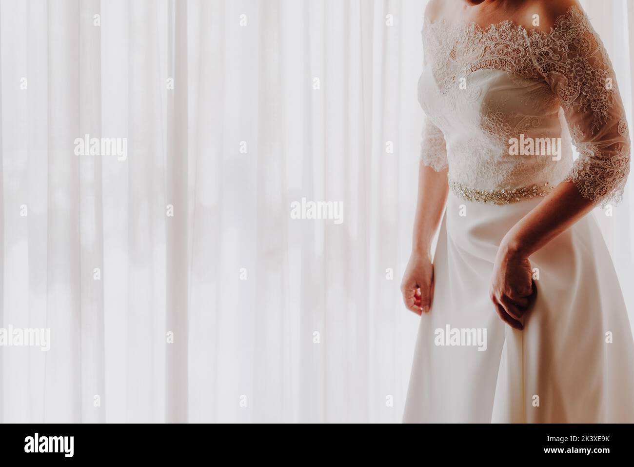 An unrecognizable bride woman in her wedding dress, with white copy ...