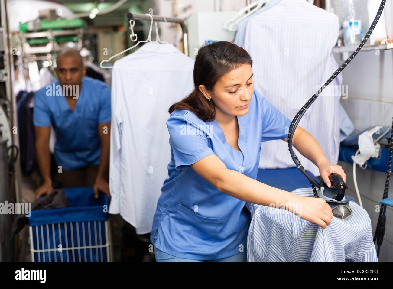 Female laundry worker ironing clean clothes in cleaning salon Stock ...