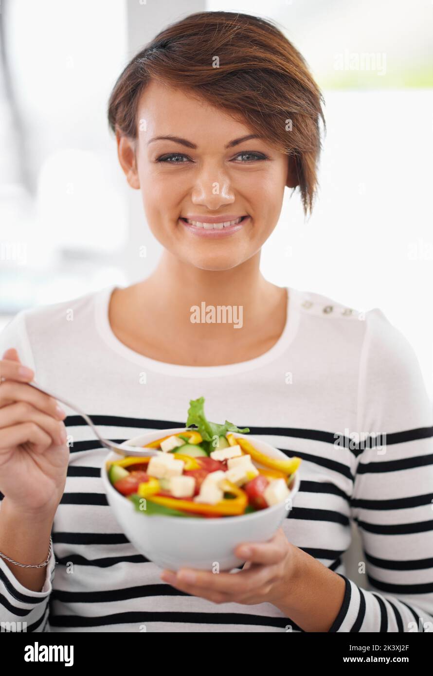 Excited about my salad. Portrait of a cheerful young woman eating salad ...