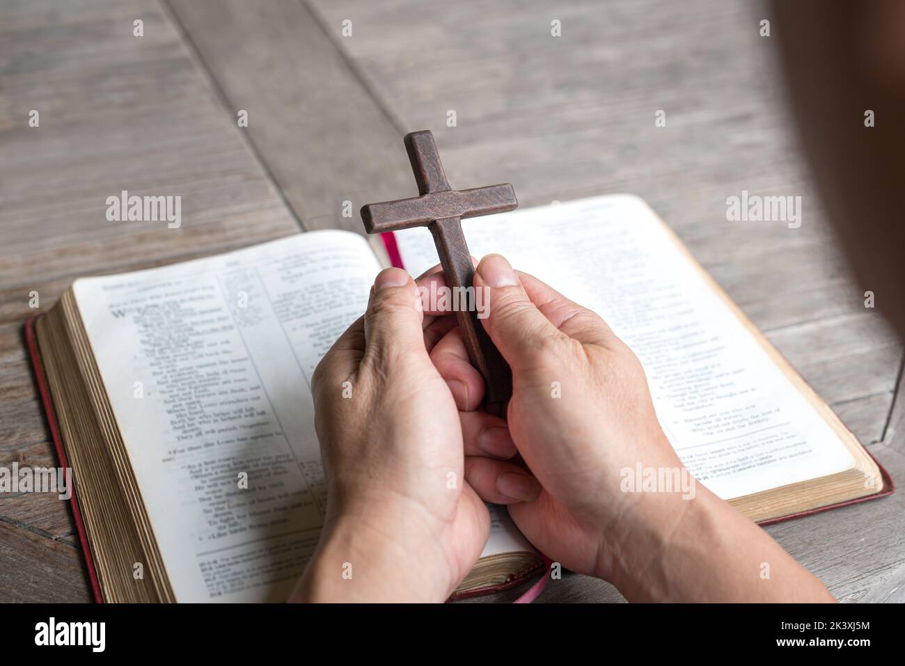 Hand holding religious crucifix cross on top of Holy Bible. Christian ...