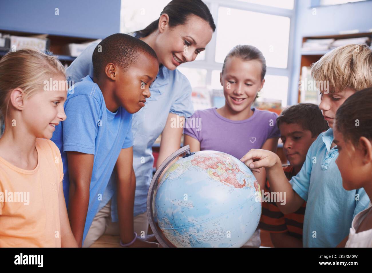 Getting to know their geography. A group of children looking at a world ...