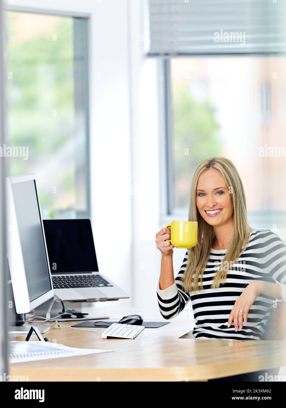 I love my job. a beautiful young woman working at her office desk while ...