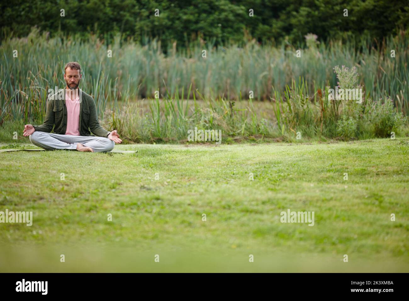 Becoming one with nature. a handsome mature man meditating in the lotus ...