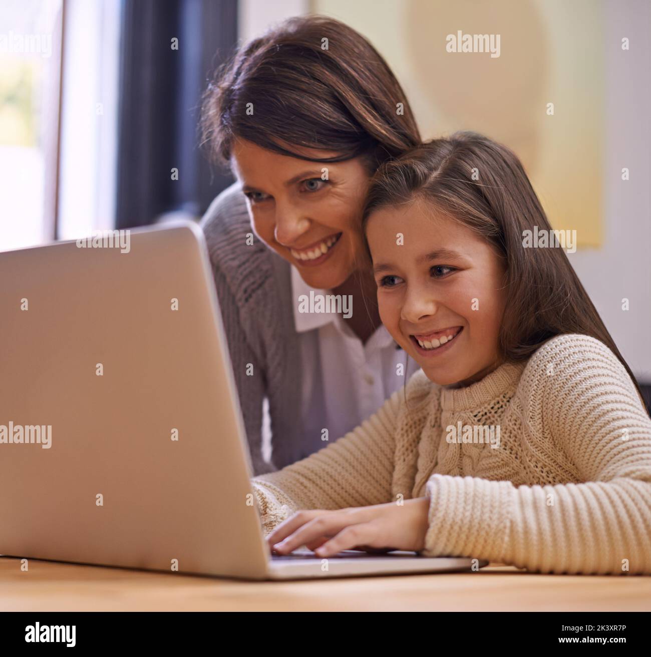 Exploring the web together. a young girl studying with her mother ...