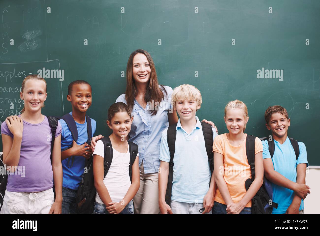 Happy classroom full of eager minds. A happy group of students standing ...