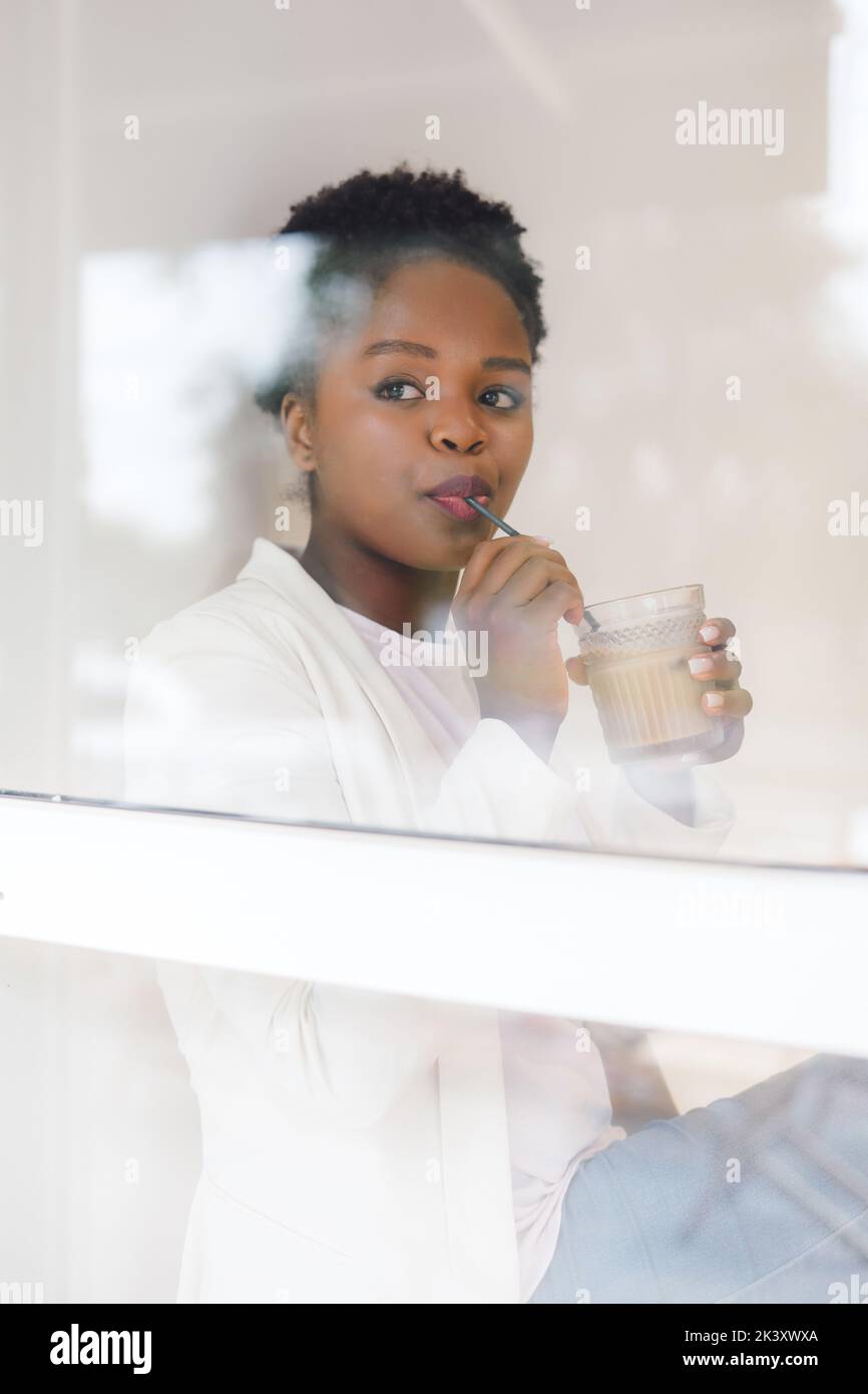 View from outside the window of an African woman enjoying a latte ...