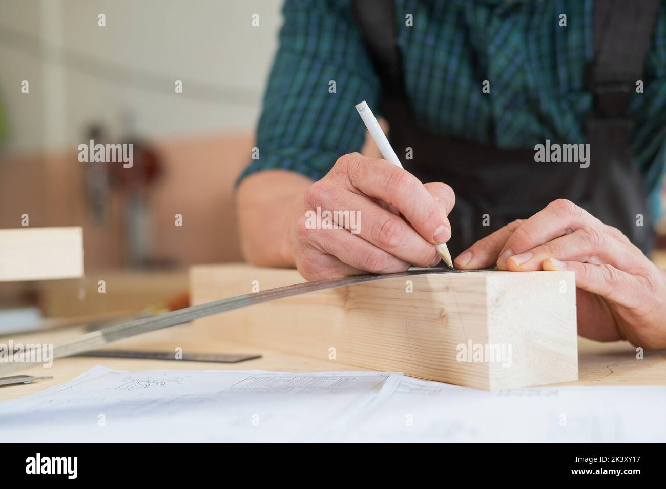 A carpenter measures wooden planks and makes marks with a pencil in a ...