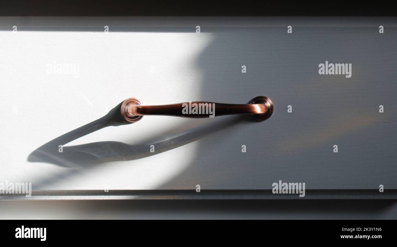 A Shiny Horizontal Copper Drawer Handle on a White Drawer Front Stock ...