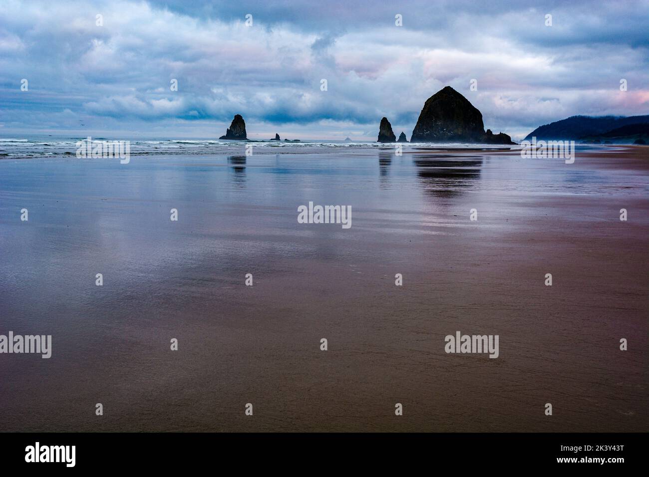 The Haystack rock on Cannon Beach under cloudy dusk sky, Oregon Stock ...