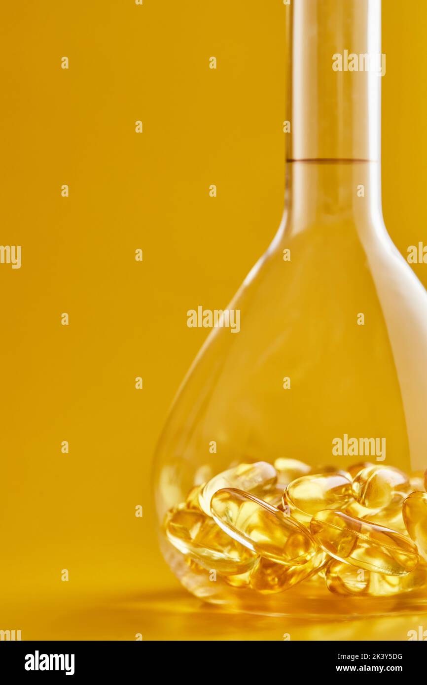 Omega-3 fatty acid capsules on a blue background in a flask. The ...