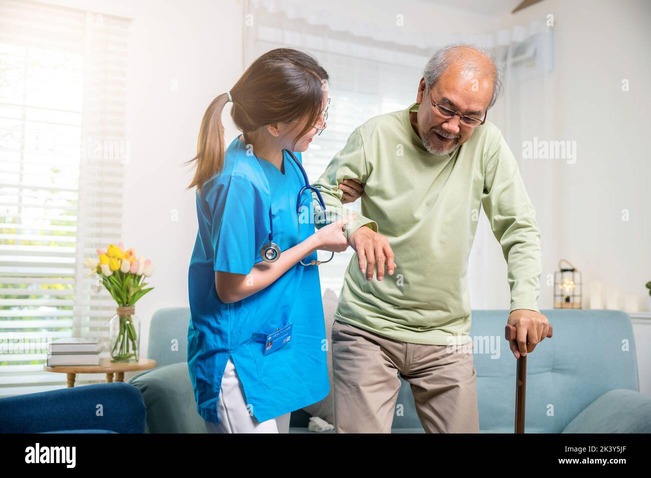 International Day for the Elderly. Young carer supporting helping senior man stand up with ...