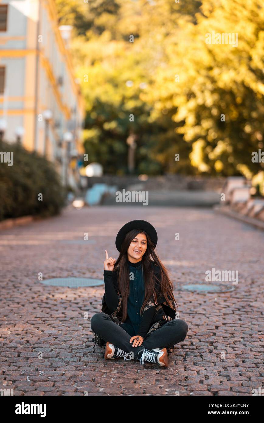 Young woman sitting at city show finger up, new idea Stock Photo - Alamy