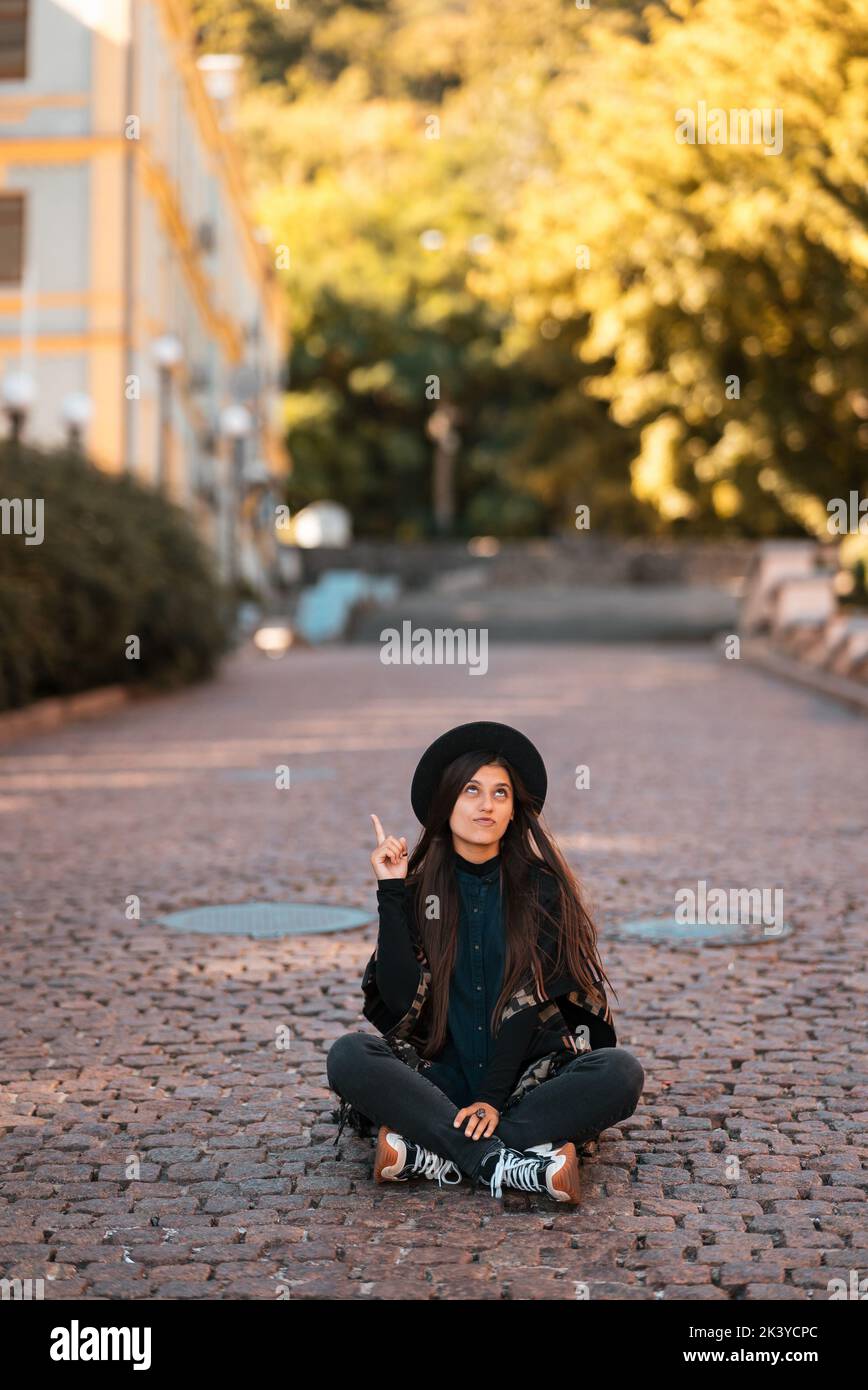 Young woman sitting at city show finger up, new idea Stock Photo - Alamy