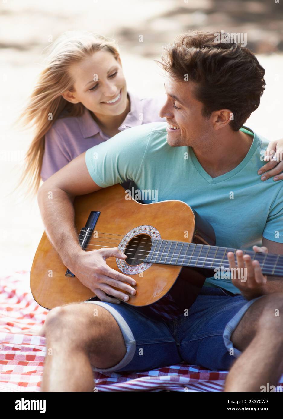 Showing his romantic side. A young man playing a song on his guitar for ...