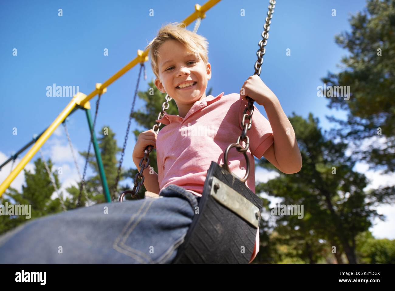 Higher and higher. A young boy enjoying the swings on the playground with friend Stock Photo - Alamy
