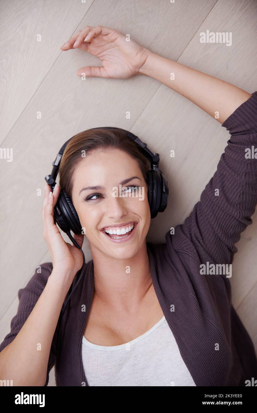 Feel the beat. A young woman smiling as she listens to music on her ...