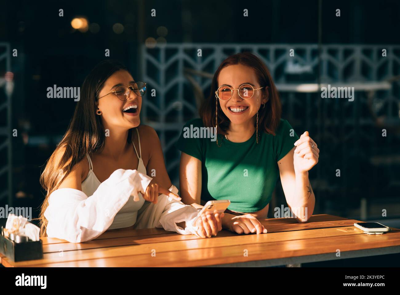 Girls using smartphones while sitting and pointing finger Stock Photo ...