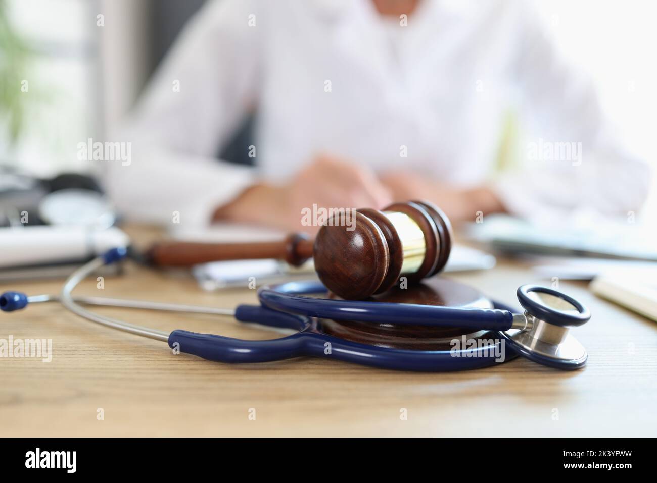Closeup of judge gavel of stethoscope doctor in background writing ...