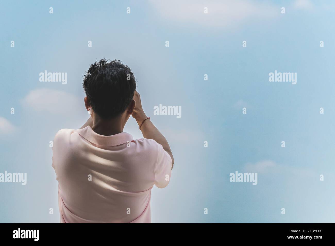 Back view of man using cell phone to take photo with cloud and sky in ...