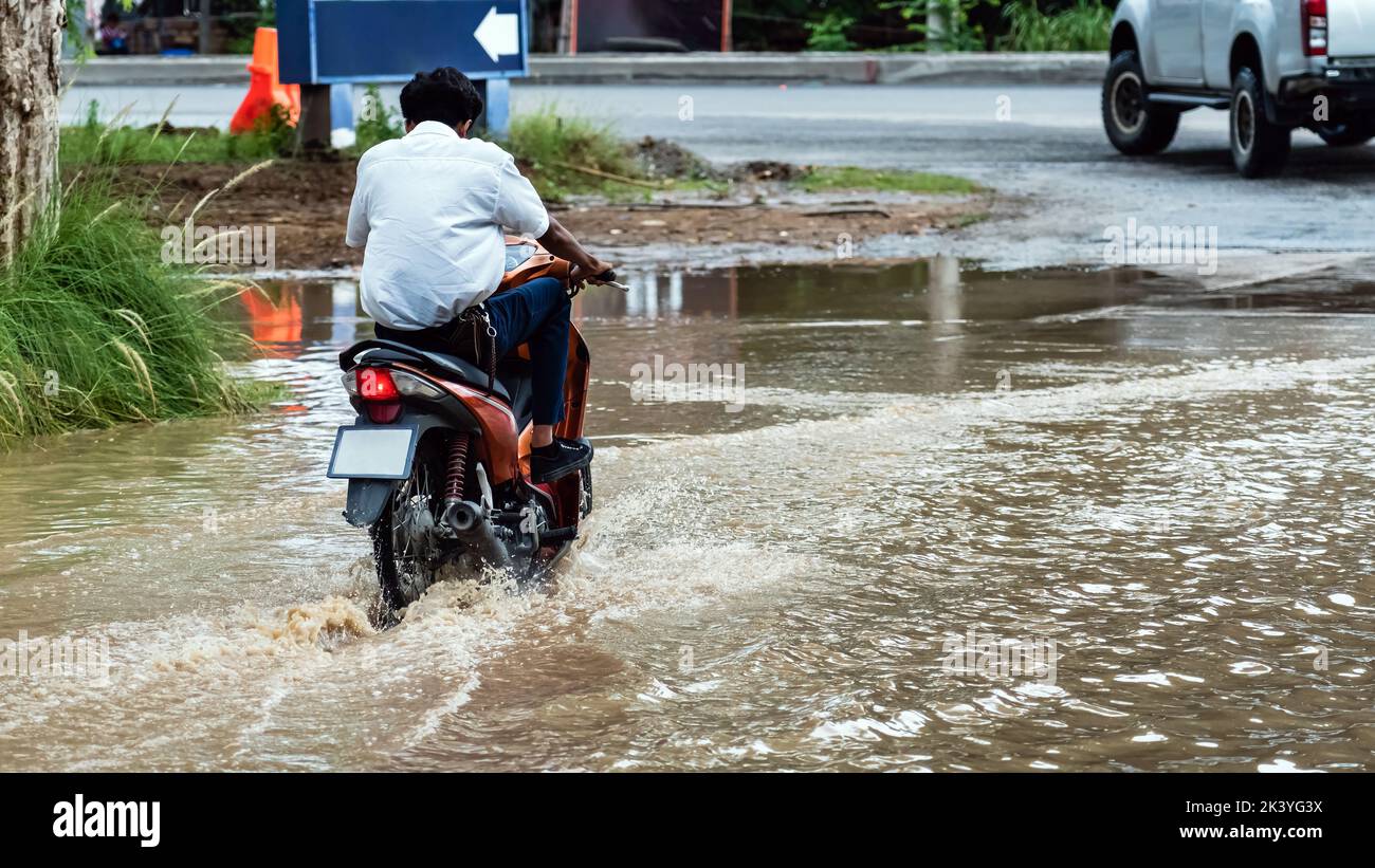 Man ride motorcycle passing through flooded road. Riding motorbike on ...
