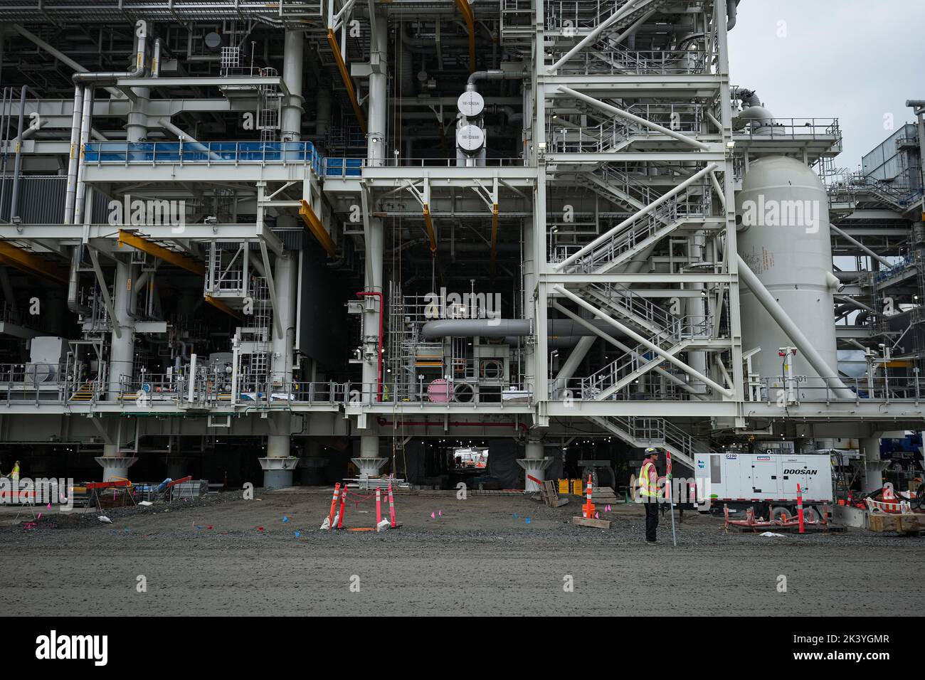 A worker holds a stop sign while controlling traffic in front of an LNG ...
