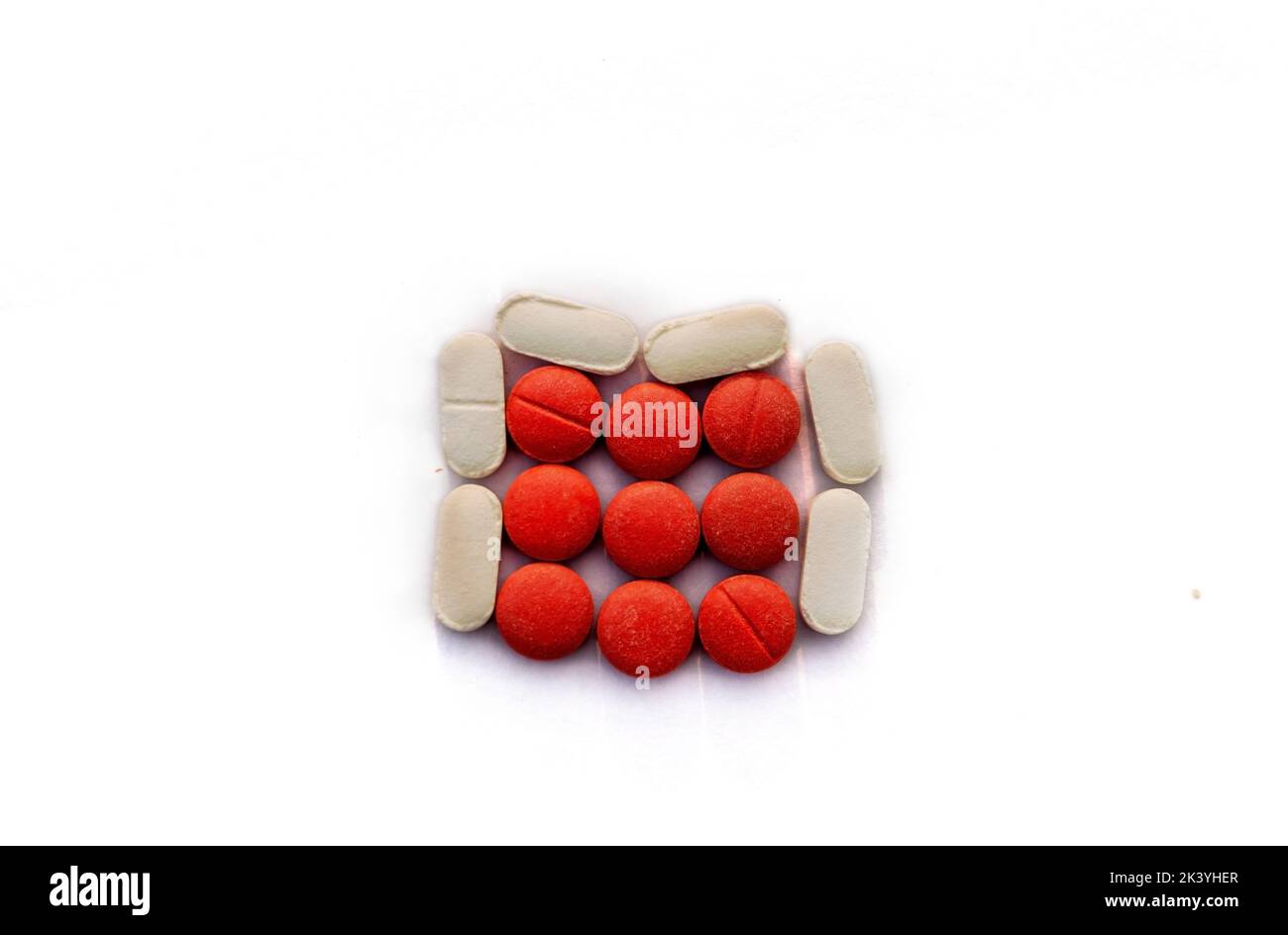 Red and White tablet medicines arranged in a square shape on a white ...