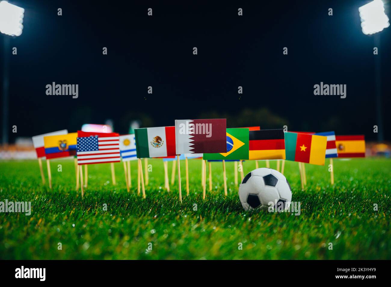 Football ball and national flags on green pitch. Including Qatar and ...