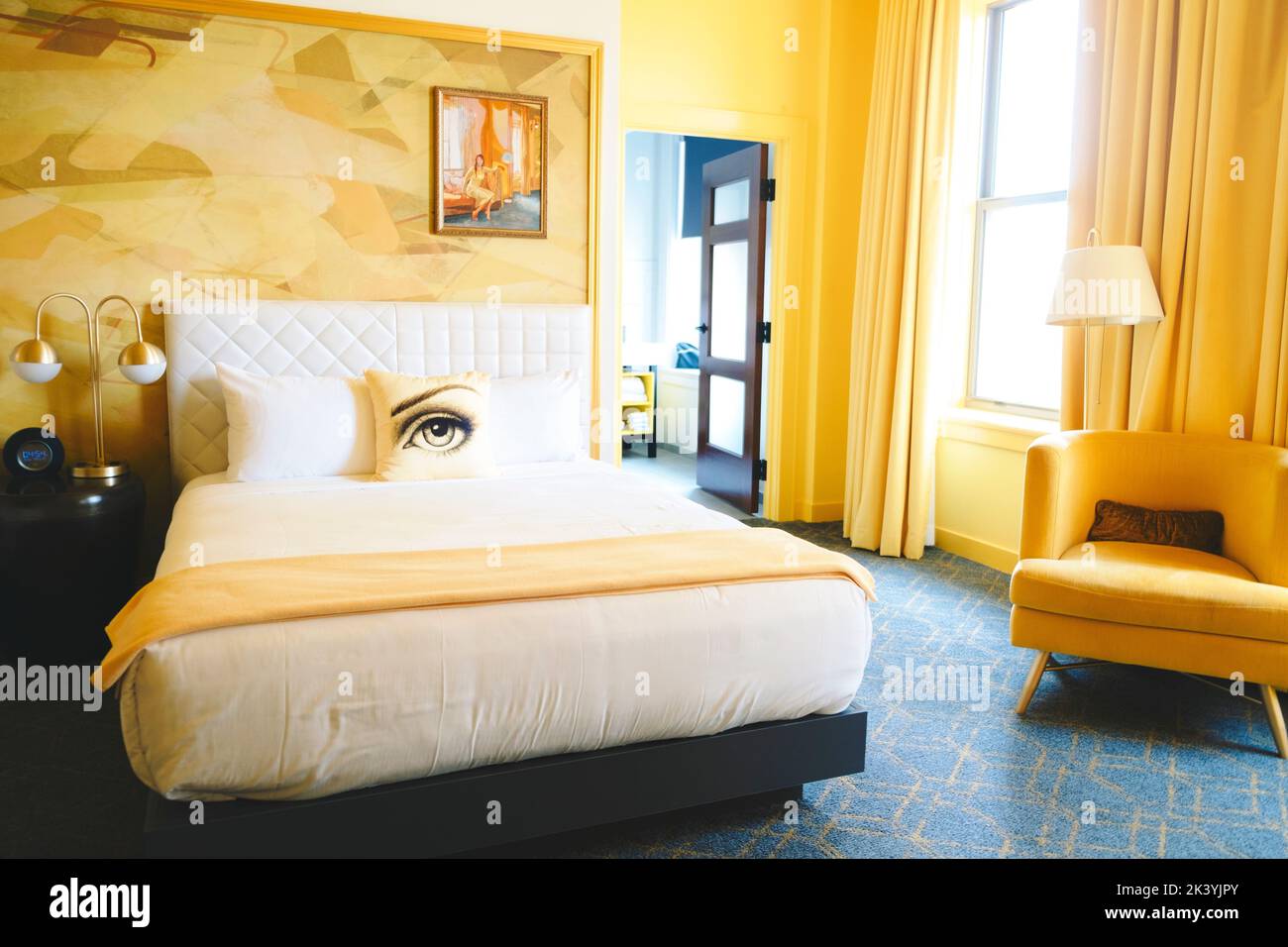 An interior of a bright, sunny yellow hotel room with art and a reading ...