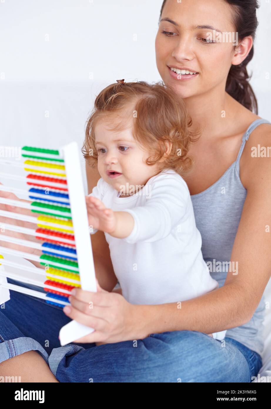 Learning at home. A young mother teaching her baby daughter the basics ...