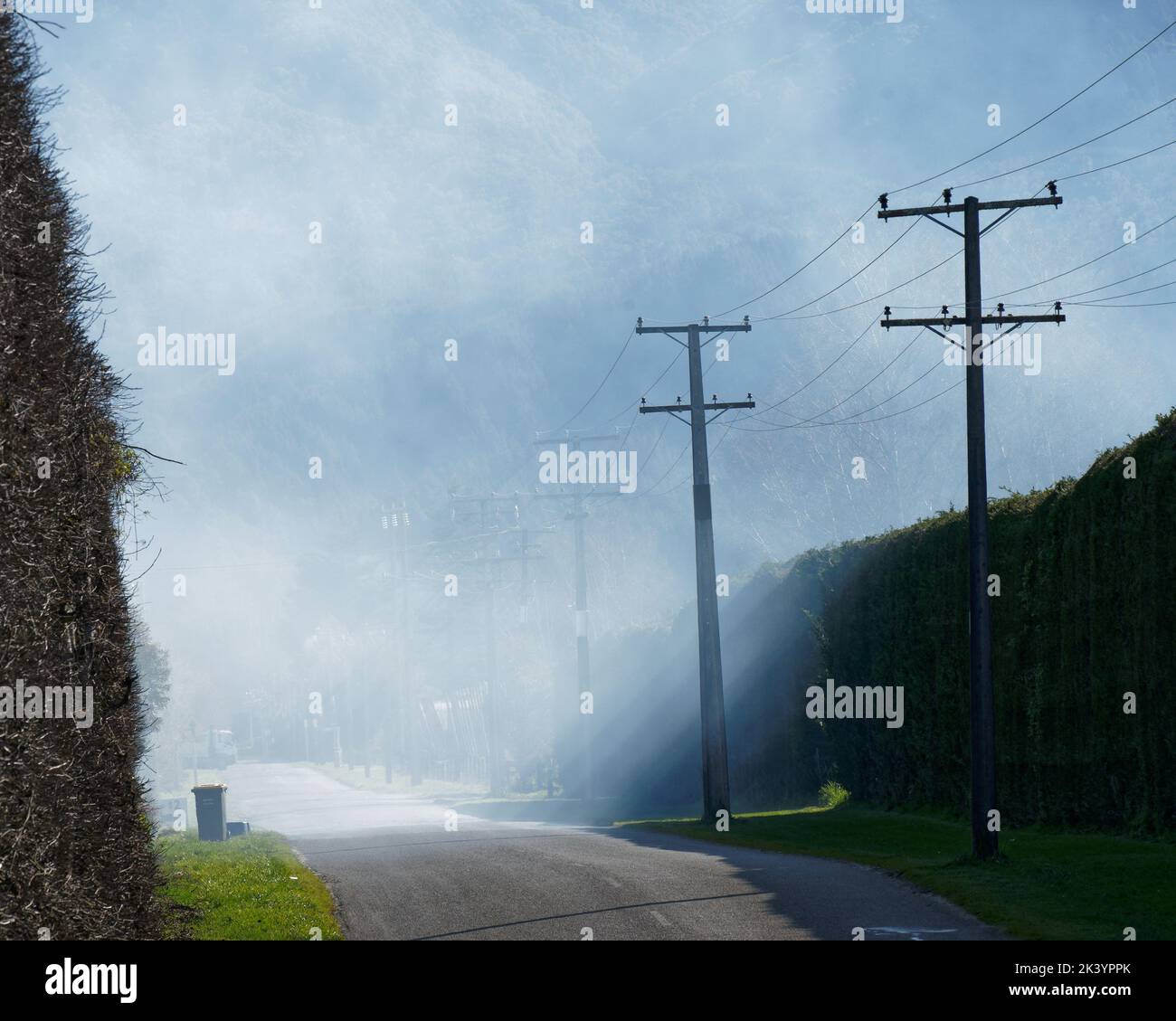 Smoke from an orchard prunings burn off bonfire obscuring a road ...