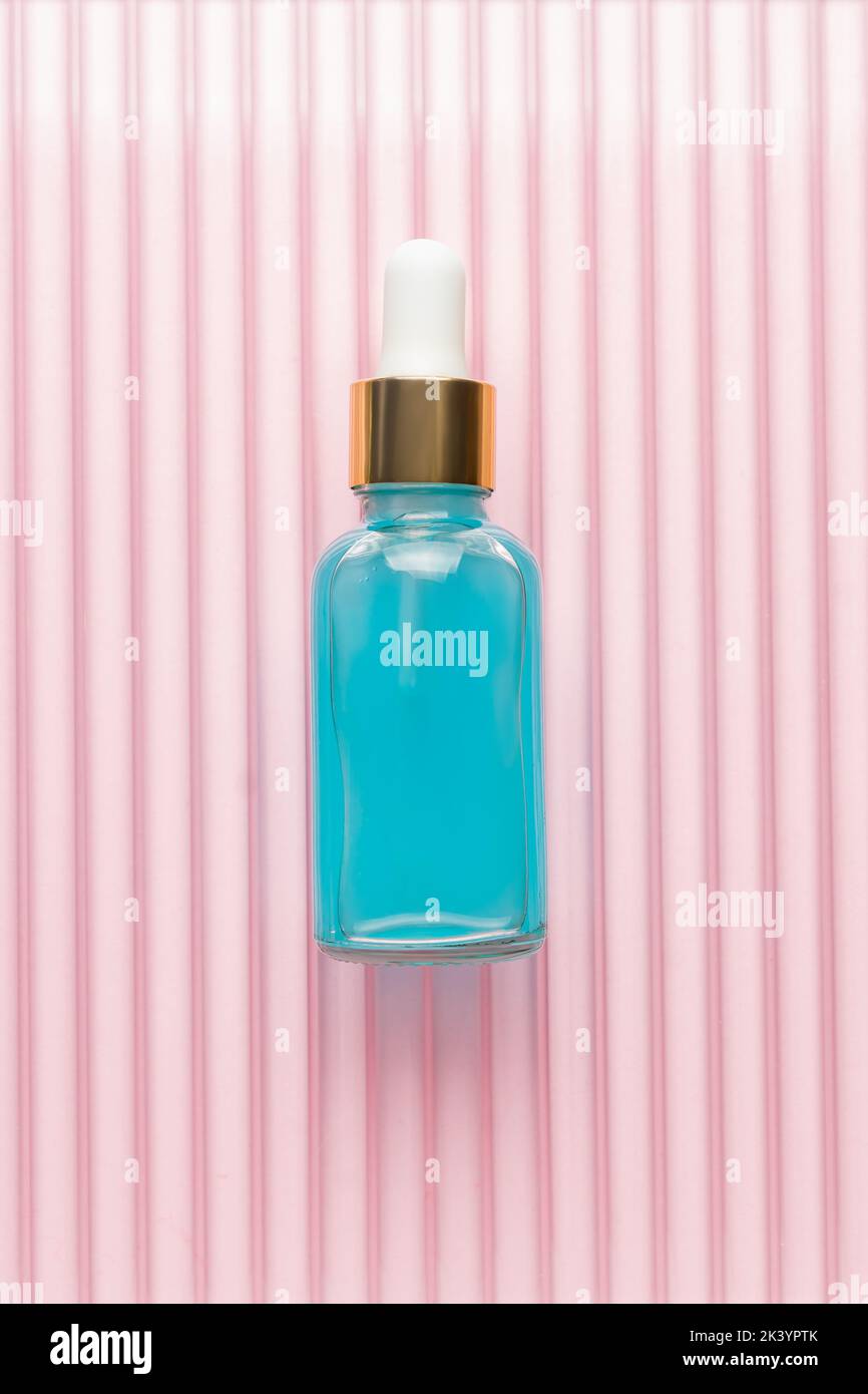 Beauty face oil in blue glass dropper bottle om pinke background ...