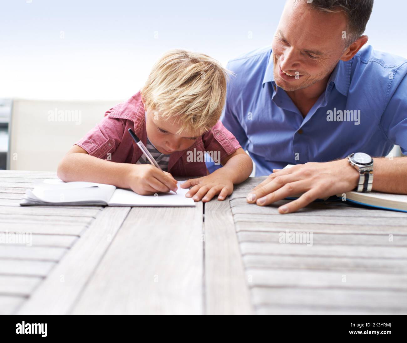 Coloring within the lines. a father helping his son with his coloring ...