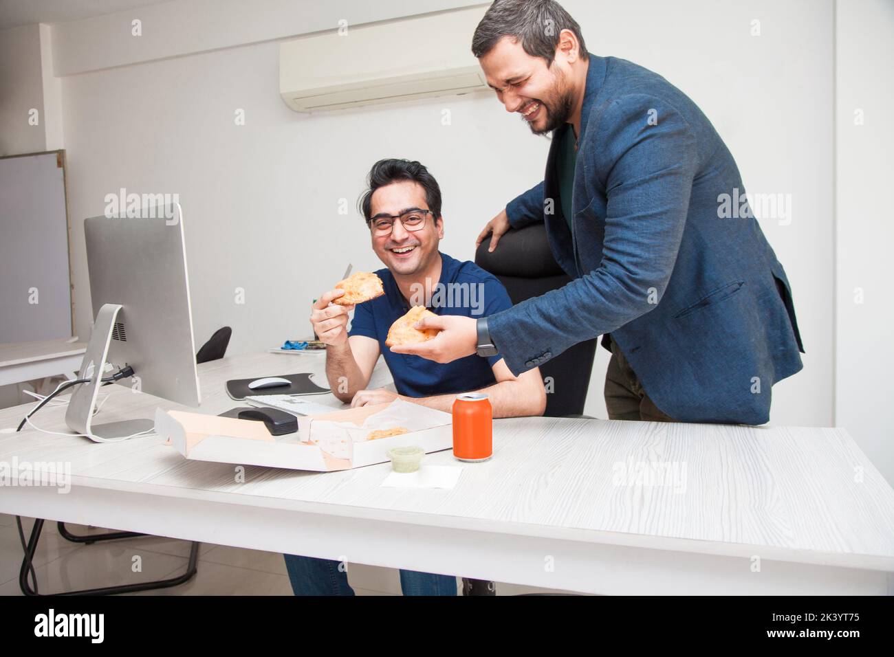 Work colleagues laughing as they share a slice of pizza at work Stock Photo - Alamy