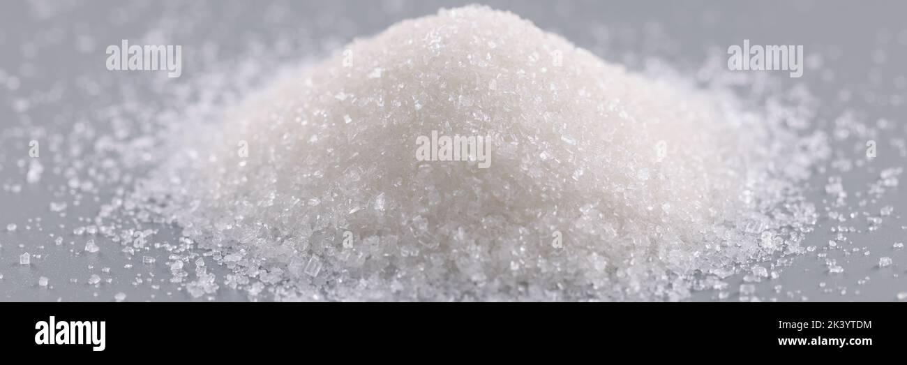 Pile of sugar crystals on grey surface, focus on heap of sweet powder ...