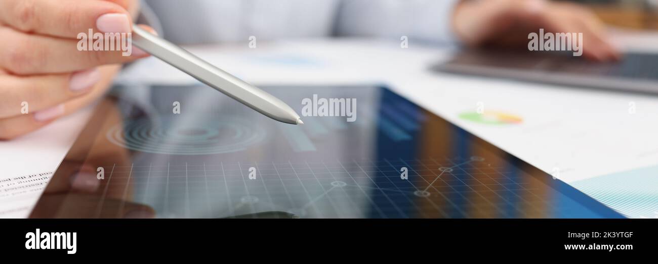 Female working on tablet with diagrams and charts on device screen ...