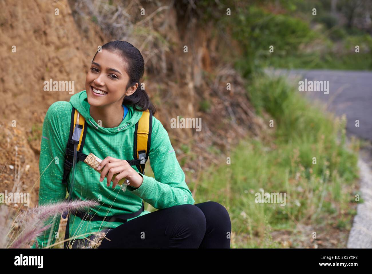 Trail snack. Cropped view of a young hiker enjoying a snack on the ...