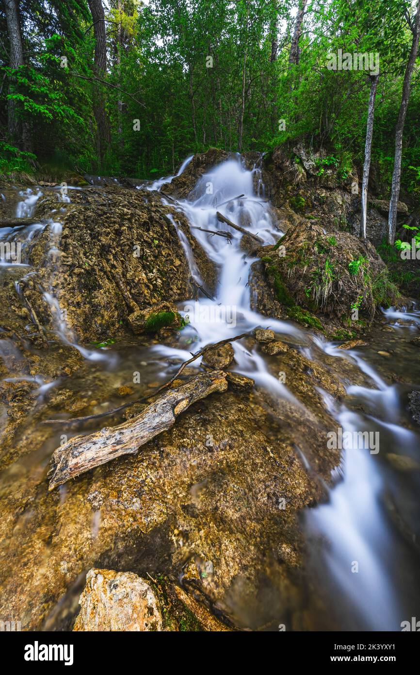 An aerial view of flowing waterfall falling from rocks surrounded by ...