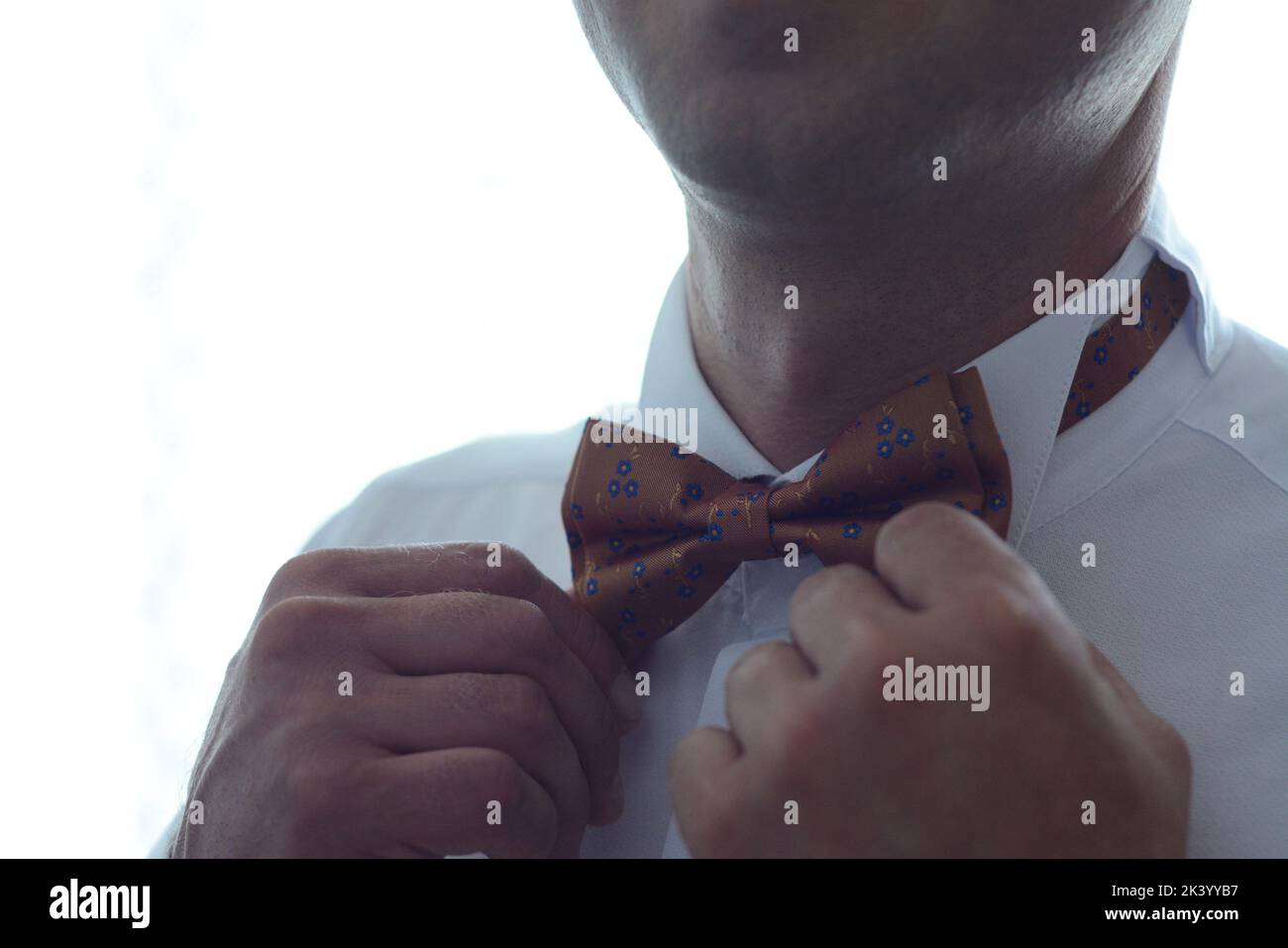 Young man putting his bow tie around his neck Stock Photo - Alamy