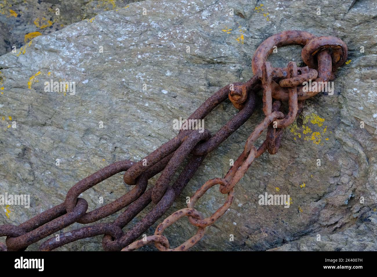 Rusty chains attached to a ring bolt set into rock Stock Photo - Alamy