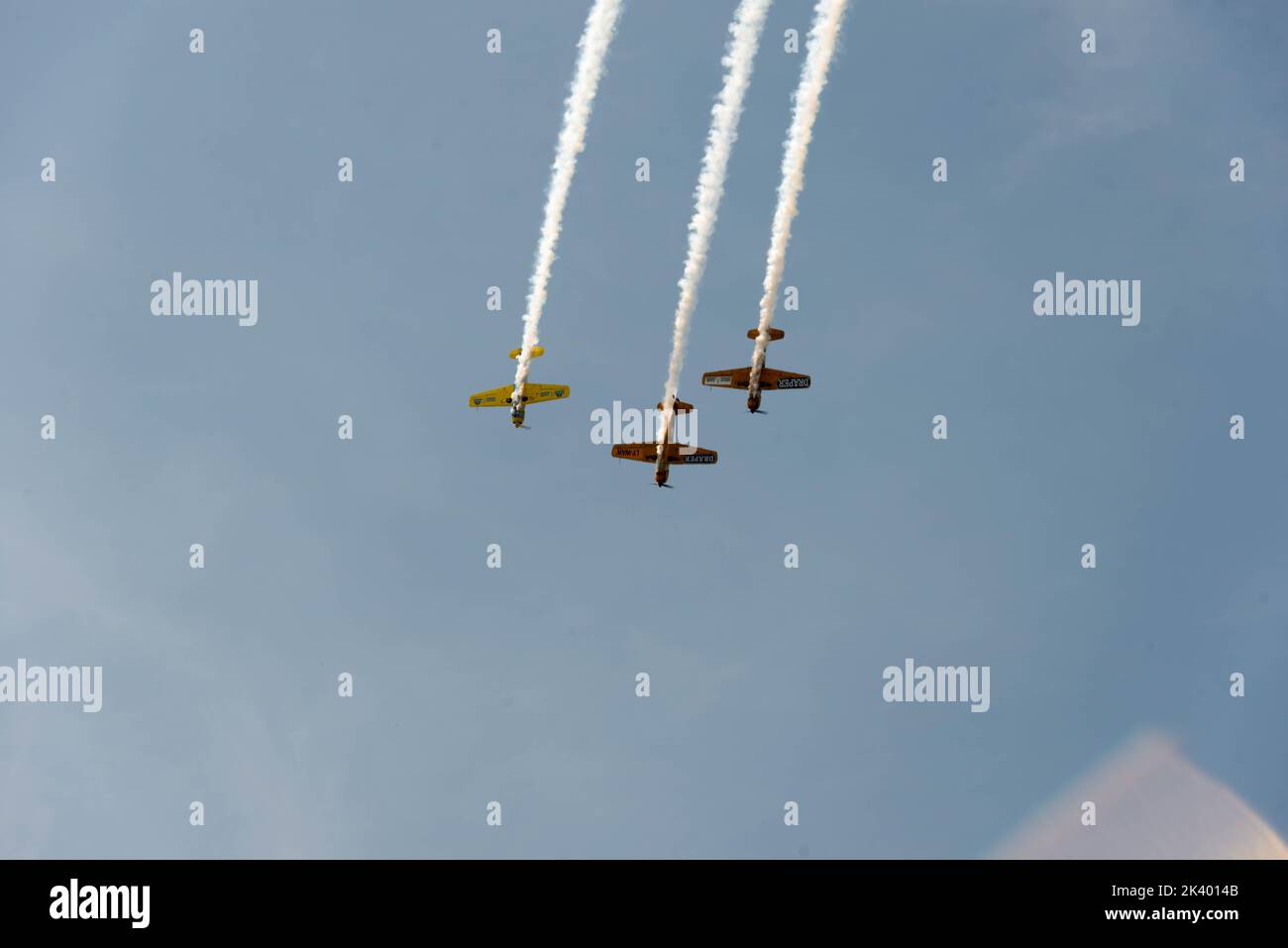 Airplane stunts on the blue sky leaving contrail Stock Photo - Alamy