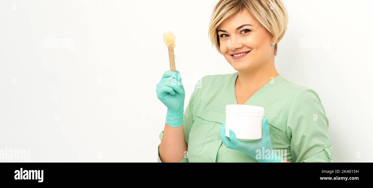 The master of sugar hair removal holds liquid yellow sugar paste, wax ...