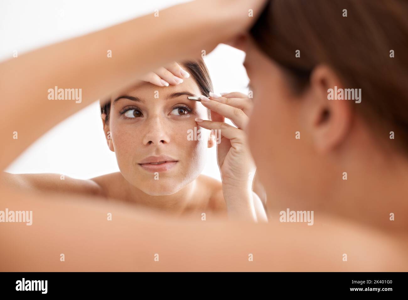 Perfecting her near-perfect face. An attractive young woman plucking ...