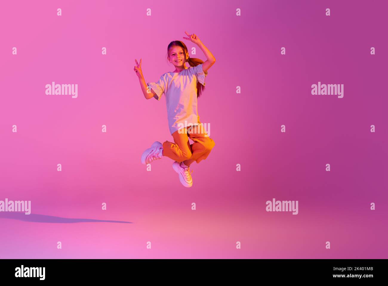 Beautiful active little girl, kid jumping, dancing isolated over pink ...