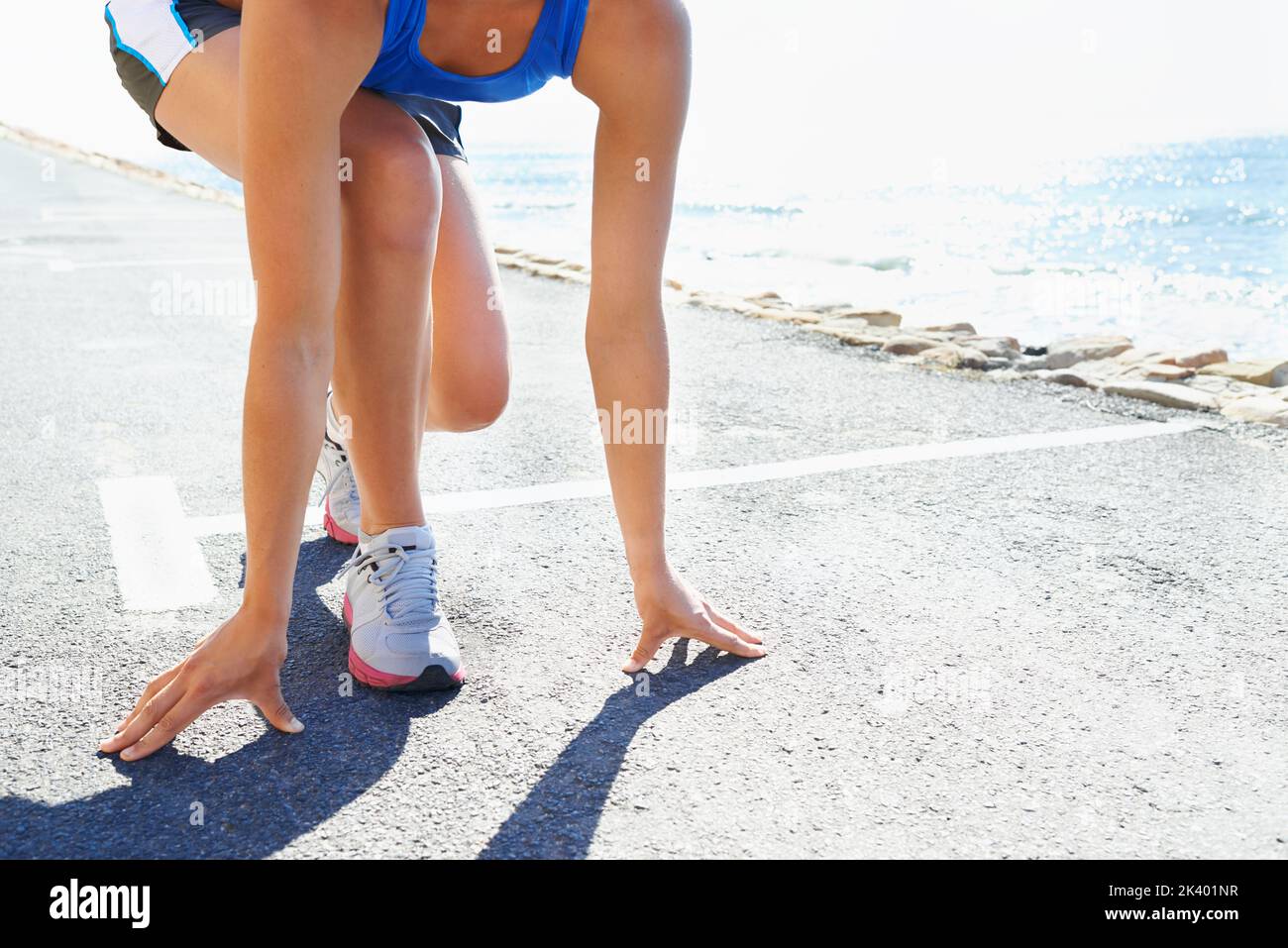 Shes ready. a young woman ready on her mark to begin her morning run ...