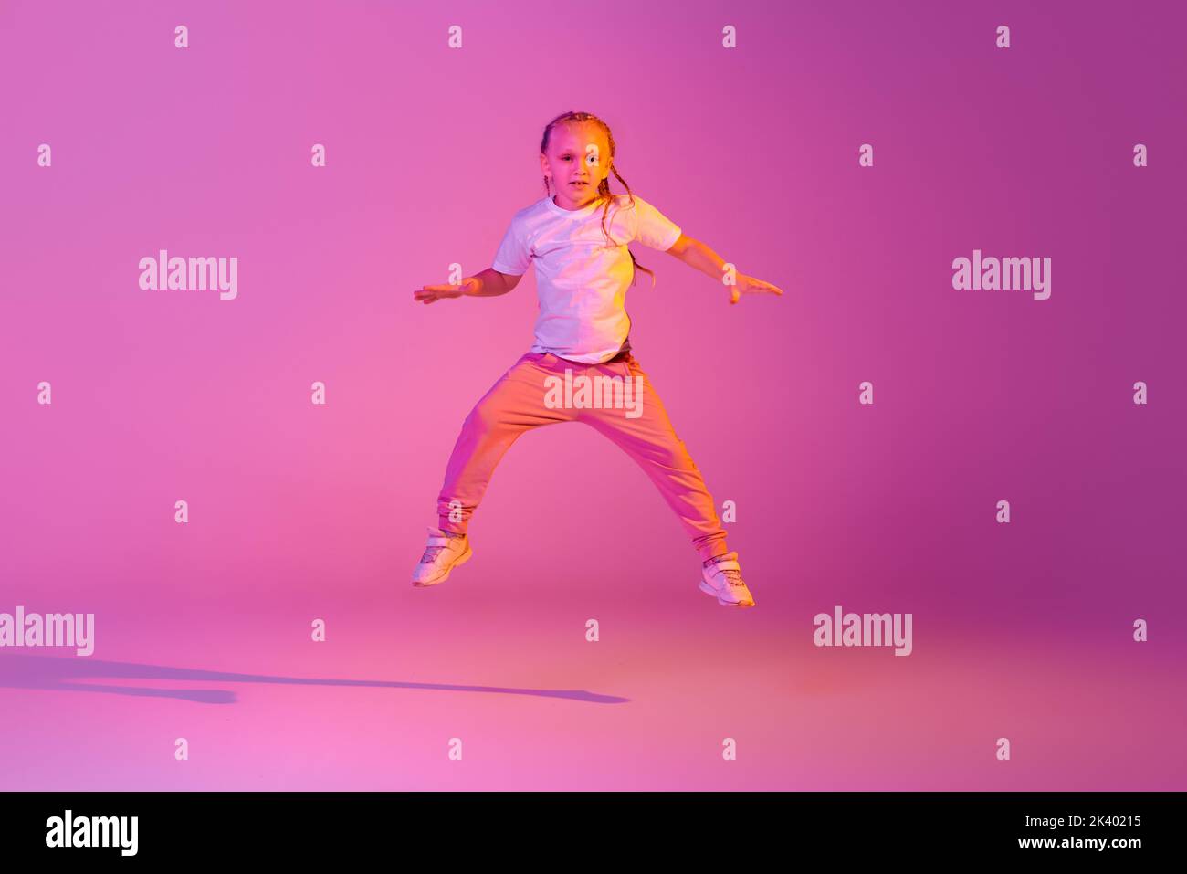 Beautiful active little girl, kid jumping, dancing isolated over pink ...